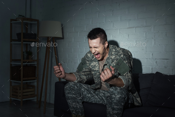 Angry soldier with post traumatic stress disorder screaming on couch at ...