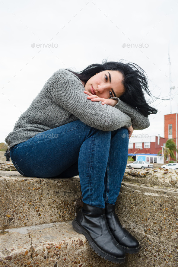 young melancholic woman sitting sad with crossed arms leaning on her ...