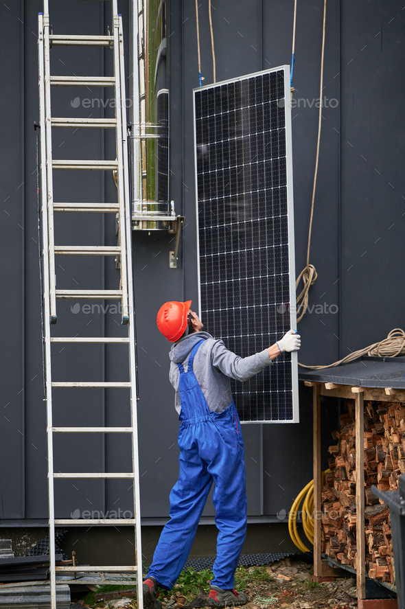 Workers lifting up photovoltaic solar module while installing solar ...