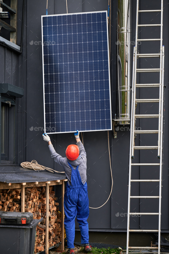 Workers lifting up photovoltaic solar module while installing solar ...