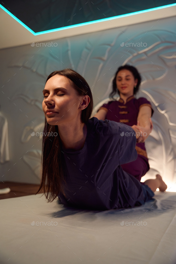 Spa practitioner stretching woman back muscles in Cobra pose Stock ...