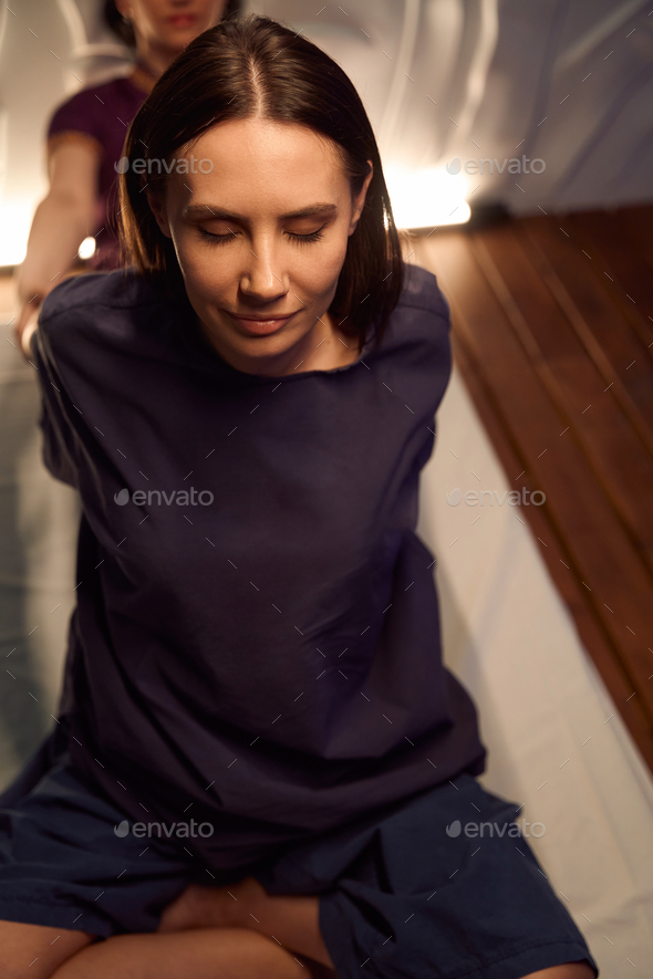 Massage practitioner stretching muscles of female patient thoracic ...