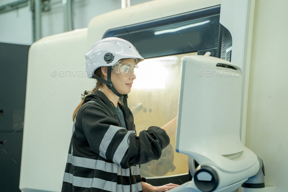 Engineer using laptop computer controlling automated robot hand with ...