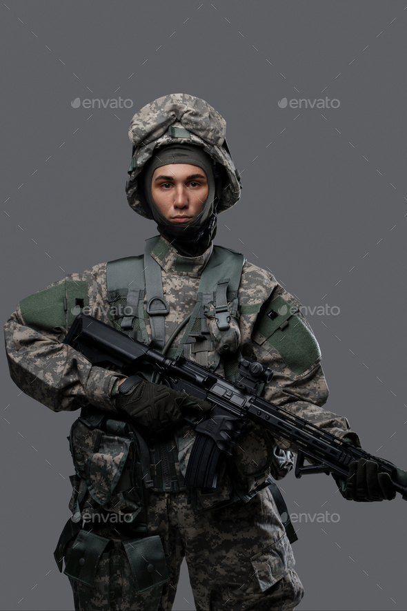 Modern Soldier holding a weapon against a grey backdrop Stock Photo by ...