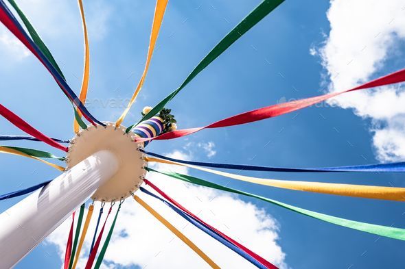 Low angle shot of the colorful bands of maypole on blue cloudy sky ...