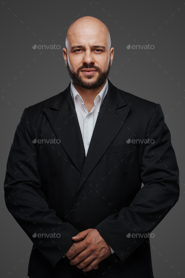 Stately bald man with a full short beard in a black suit and tie Stock ...
