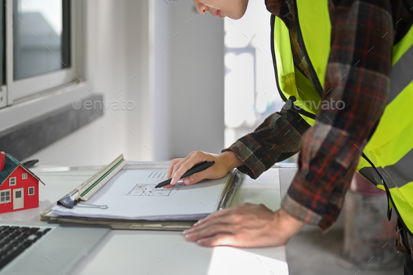 Engineer man working at blueprints and checking building construction ...