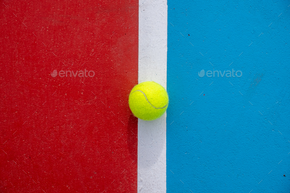 Yellow tennis ball placed on a wall colored with red, blue and ...