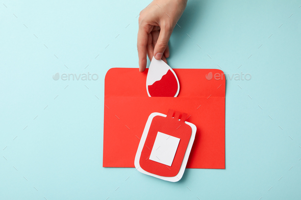 Paper container of blood in the hand on a blue background. Blood ...