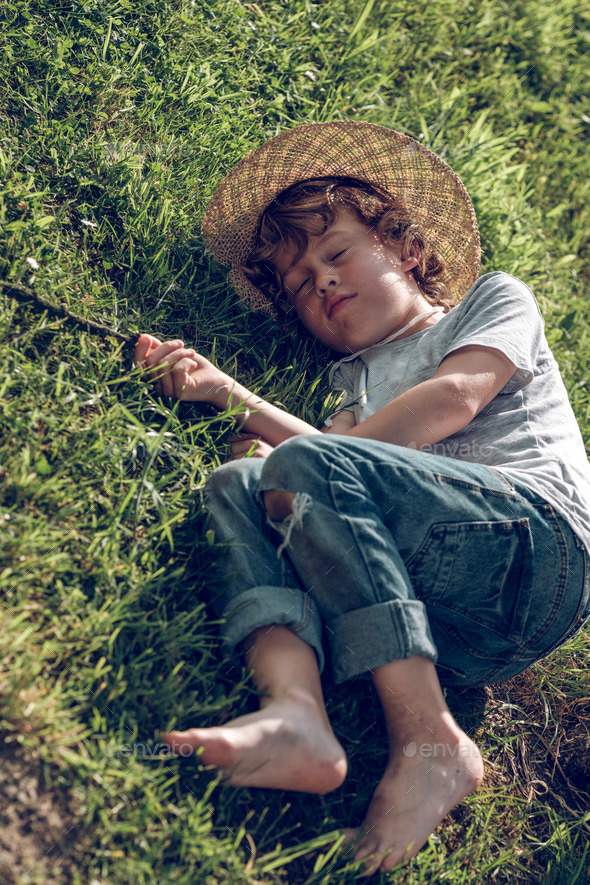 Adorable preteen boy napping on grass in sunny day Stock Photo by ...