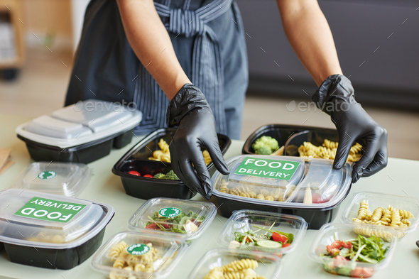 Woman carefully packing food delivery orders in plastic containers ...