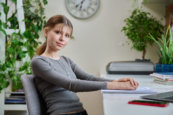 Portrait of teenage girl sitting at desk at home with laptop computer ...