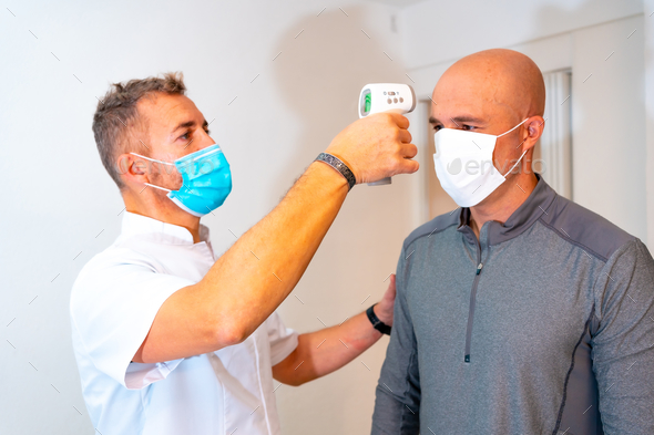 Healthcare professional measuring the temperature of the patient ...