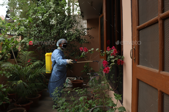 Professional worker in PPE uniform using sanitizing spray Stock Photo ...