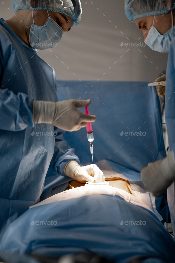 Surgeon makes an injection during an operation Stock Photo by RossHelen