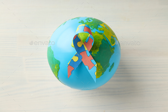 Ribbon with multi-colored puzzle pieces and a model of the planet Earth ...