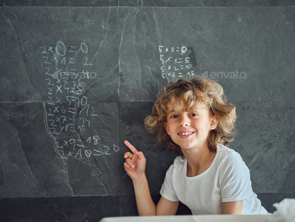 Smiling child solving math equations Stock Photo by ADDICTIVE_STOCK
