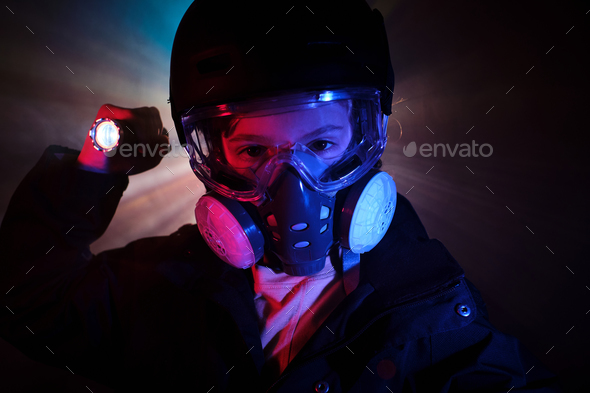 Boy in gas mask shining flashlight in dark studio Stock Photo by ...