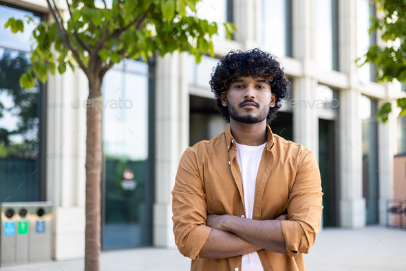 Portrait of a young serious Indian male programmer standing outside an ...