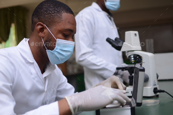 Scientist microbiologists with uniforms working with test tubes and a ...