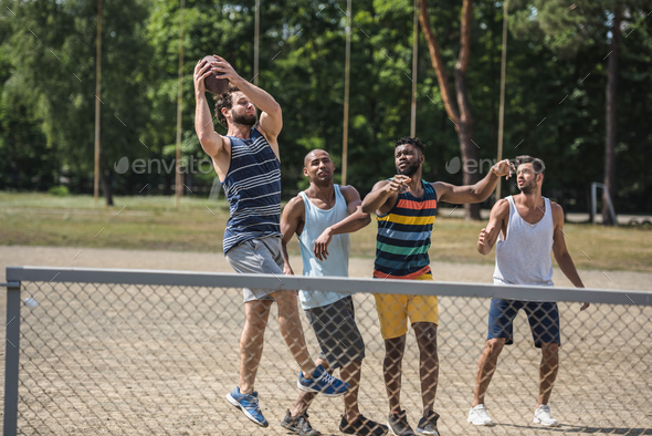 group of young multicultural men playing football on court Stock Photo ...