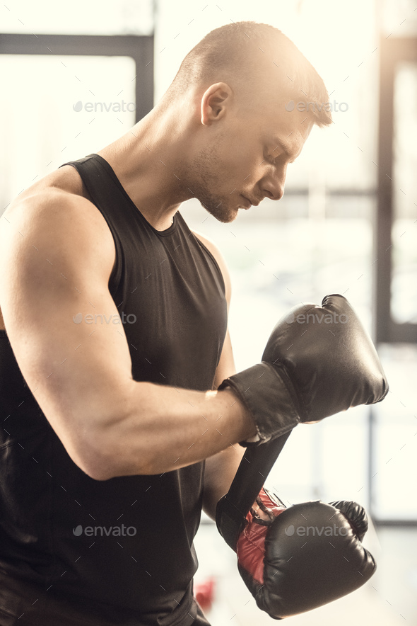 side view of muscular young sportsman wearing boxing gloves Stock Photo ...