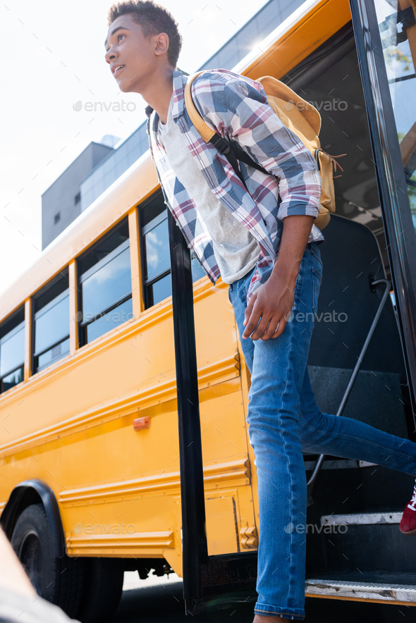 bottom view of teen african american schoolboy walking out school bus ...