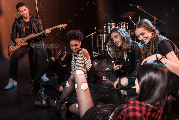 Young rock and roll band sitting together and drinking beer after ...
