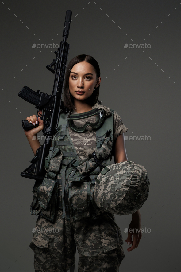 Beautiful female soldier in military uniform stands holding an ...