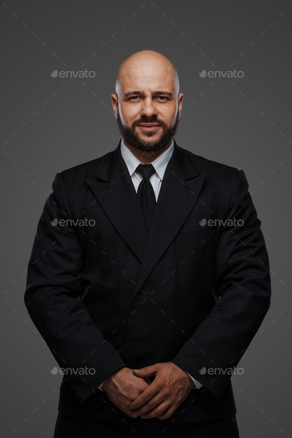 Stately bald man with a full short beard in a black suit and tie Stock ...