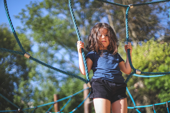 Caucasian girl stands on a rope swing in a park on a playground Stock ...