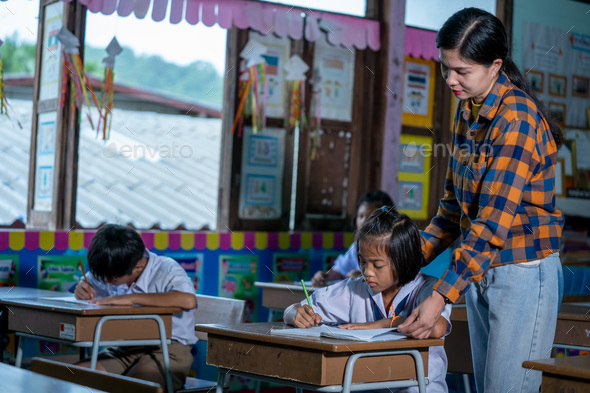 Elementary school teacher helping student in classroom,Education ...