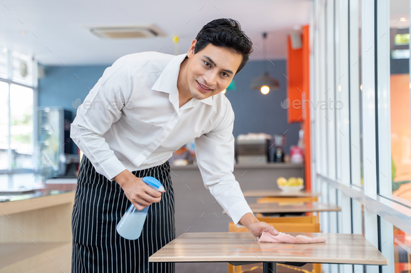Waiter cleaning the table with Disinfectant Spray in a cafe. Stock ...