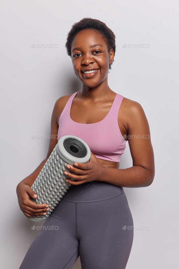 Smiling dark skinned healthy woman going to massage back muscles with ...