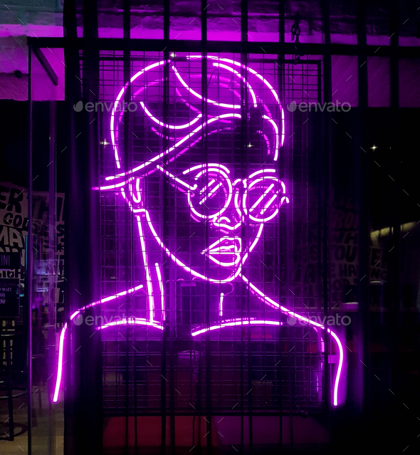 Creative sign with purple neon lights in the shape of a female portrait ...