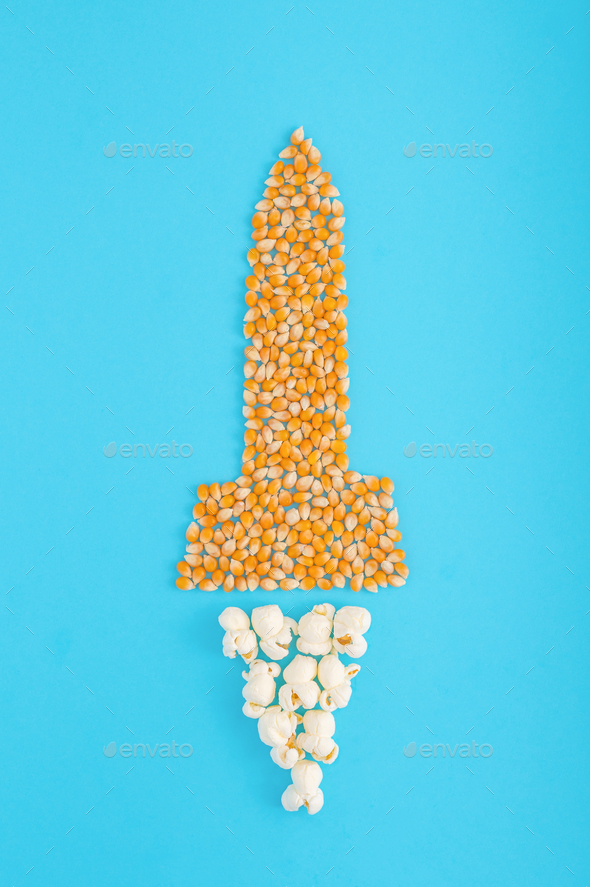 Vertical shot of a rocket figure made of corn on a blue background ...