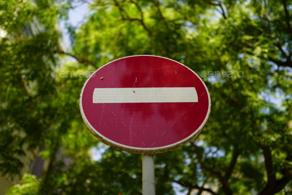 Low angle shot of a stop sign along the road on a blurry tree branches ...