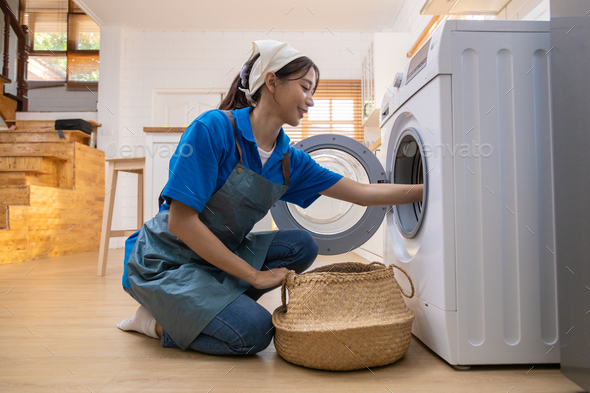 Young housewife doing laundry, drying, spinning with automatic washing ...
