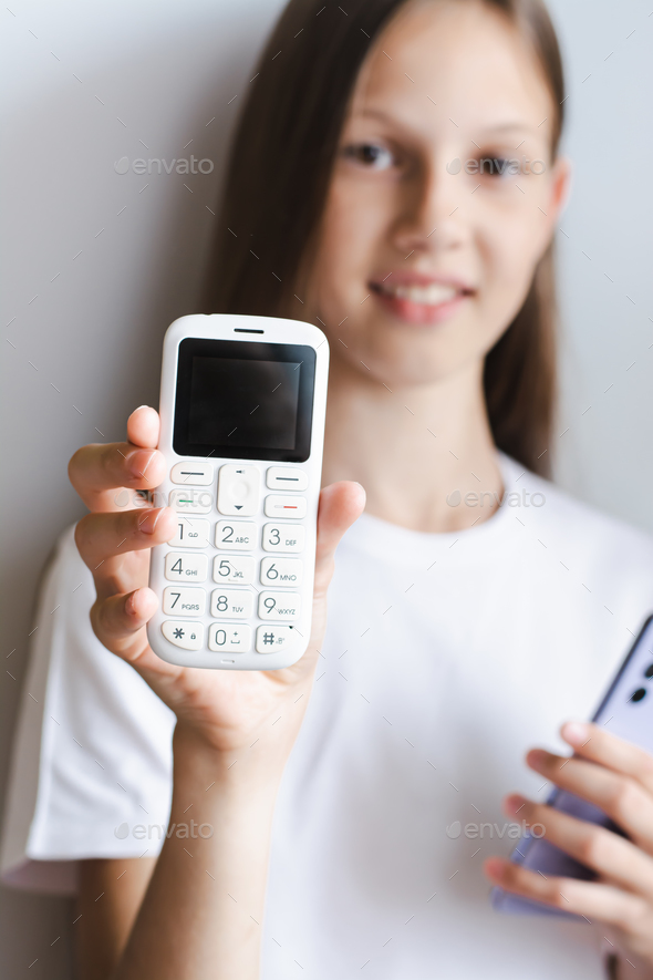 White push-button telephone in the hand of a girl with a smartphone ...