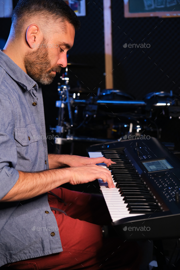 Musician man playing keyboard synthesizer piano in a recording studio ...