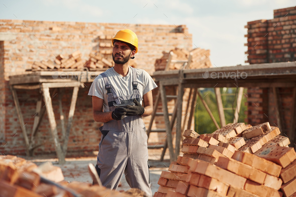 Wearing the gloves. Handsome Indian man is on the construction site ...