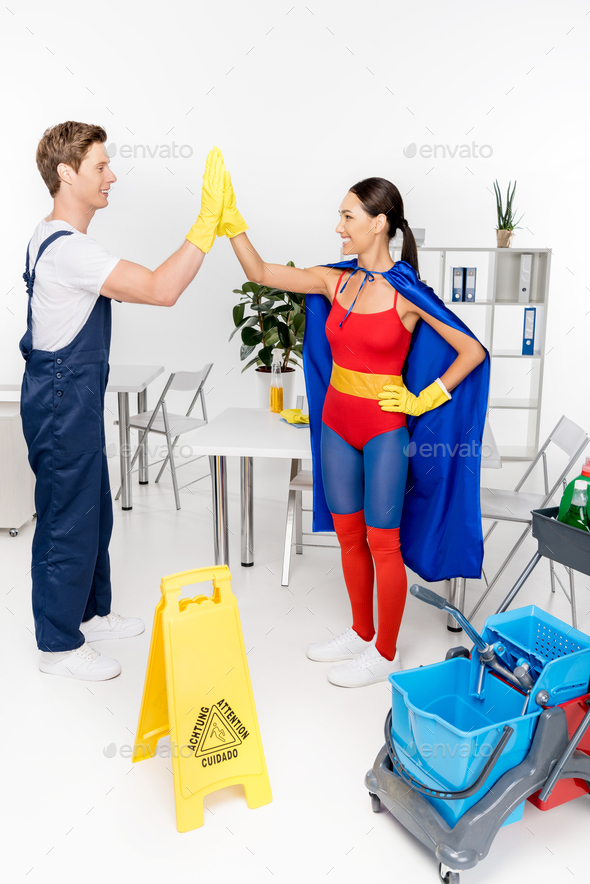 side view of cleaner and woman in superhero costume giving each other ...