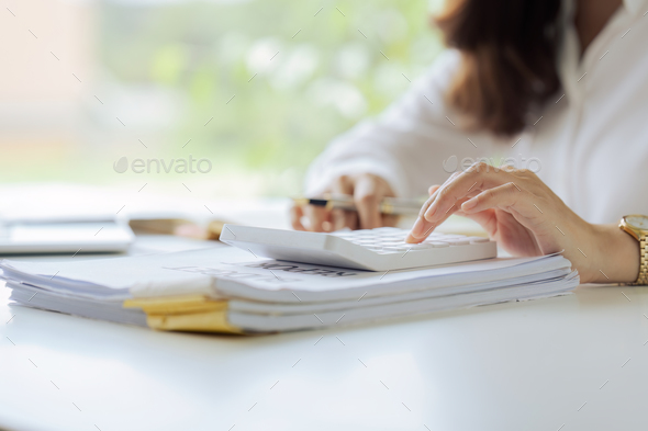 Businesswoman using a calculator to calculate numbers on a company's ...