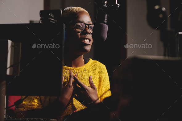 Black woman speaking into microphone in recording studio Stock Photo by ...
