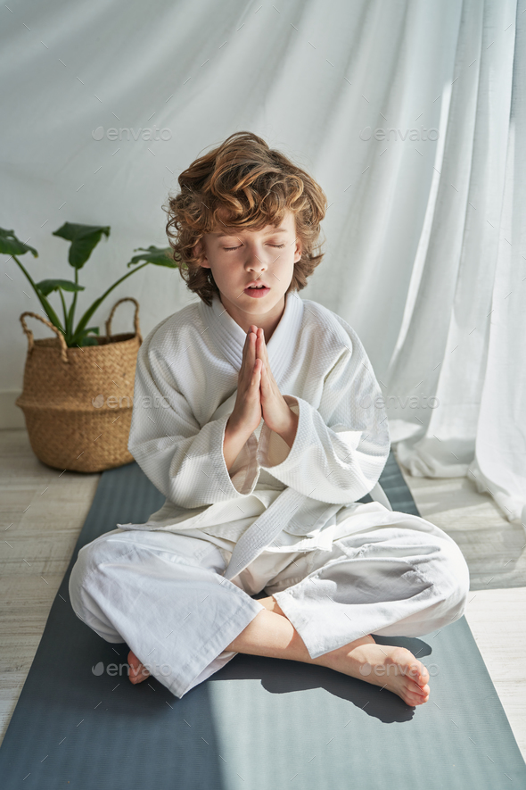 Calm boy in kimono meditating in Lotus pose Stock Photo by ADDICTIVE_STOCK