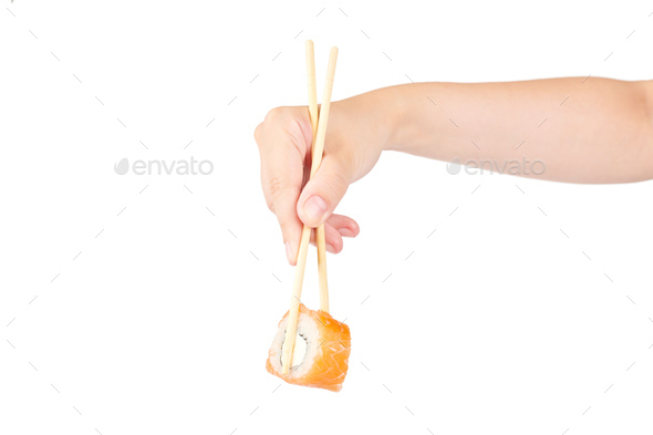 Female hand holding Philadelphia maki roll with bamboo chopsticks isolated on white background ...