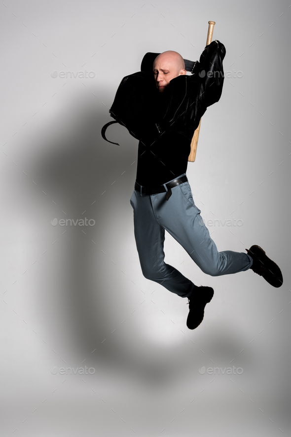 aggressive bald man in leather jacket holding baseball bat and jumping ...