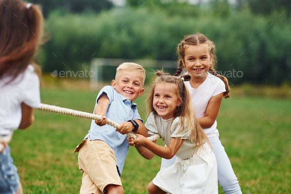 Holding the rope, playing game. Kids are having fun on the field at ...