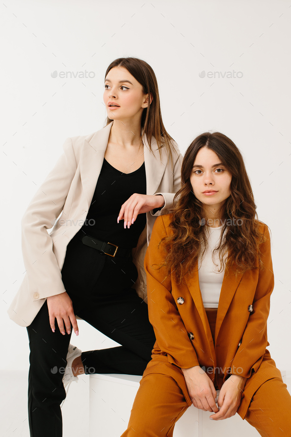 Model women dressed in fashionable pastel blazers posing on a cube on a ...