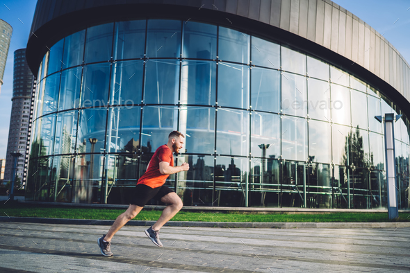 Fit male athlete practicing running near modern building Stock Photo by ...